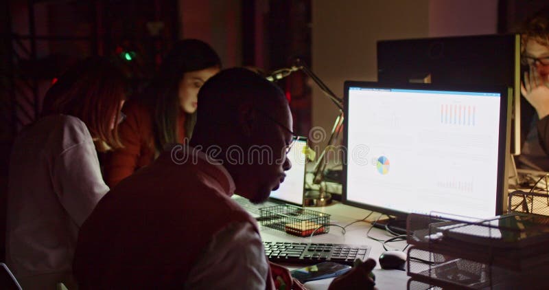 Colleagues in a Dimly Lit Office Work Diligently on a Project, with ...