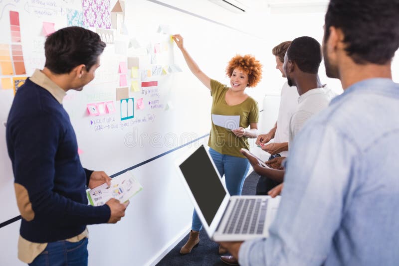 Colleagues Looking at Businesswoman Explaining Plan on Whiteboard Stock ...