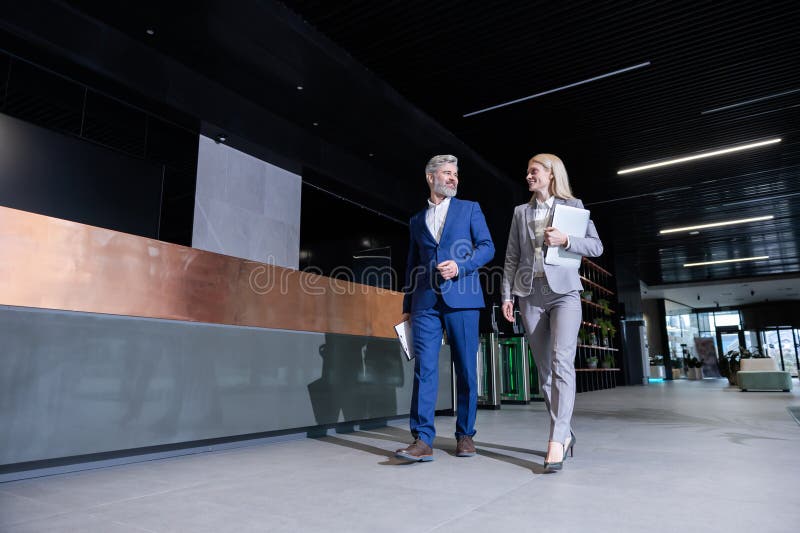 Colleagues Moving through Workplace Talking about Professional ...