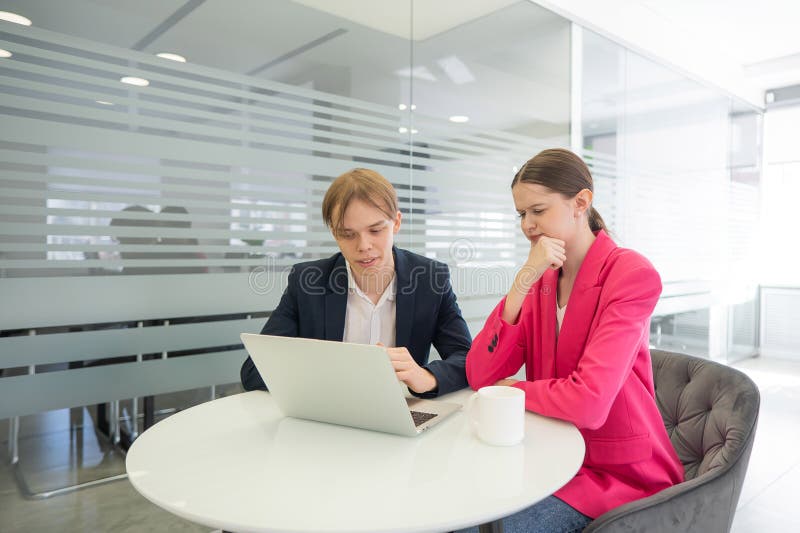 Colleagues are Sitting at the Same Table and Looking at a Laptop. Stock ...