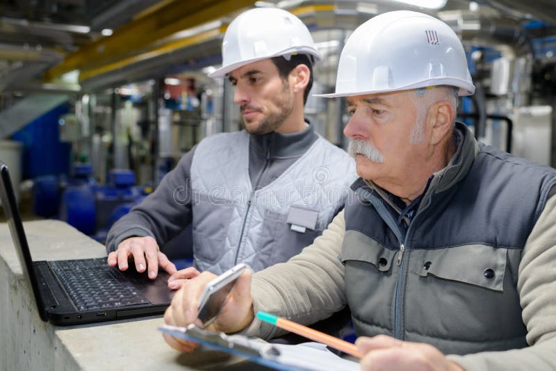 Colleagues Wearing Hard Hats Checking Document Stock Image - Image of ...