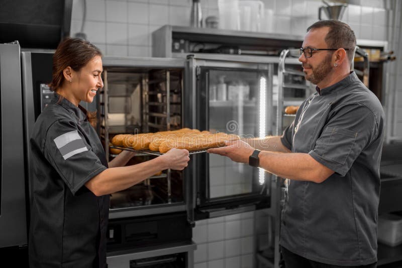 Colleagues Working in a Bakery and Holding a Tray with Fresh Buns Stock ...