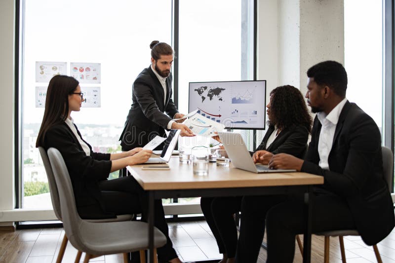 Businessman Handing Out Paper Tasks during Team Meeting Stock Photo ...