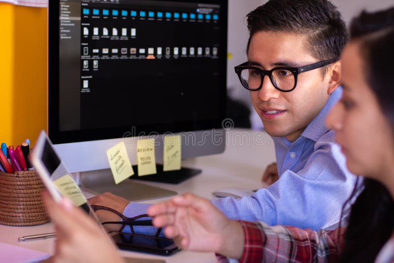 Colleagues Working Together Using Digital Devices and a Computer in an ...