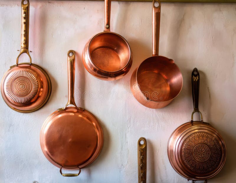 A Collection of Antique Copper Cookware Hanging on a Wall Stock ...