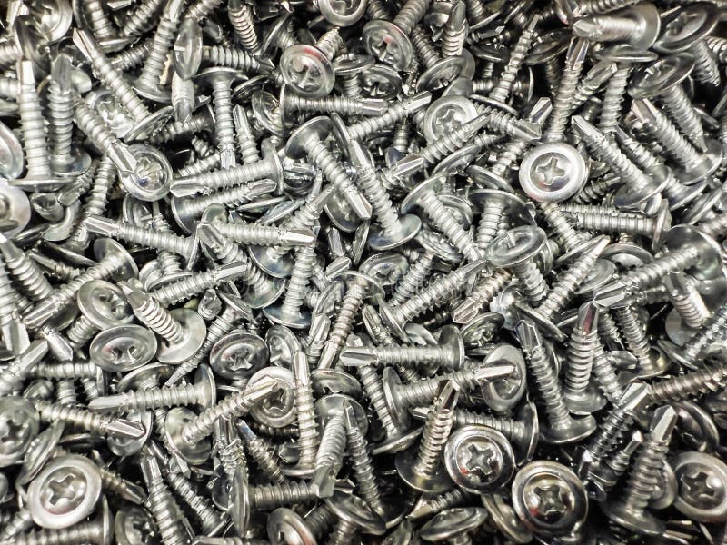Collection of Metallic Screws Scattered Across a Flat Surface in a ...
