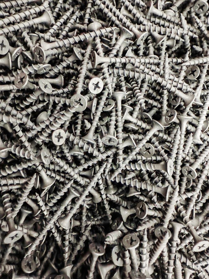 Collection of Numerous Black Screws Spilled Across a Surface in a ...