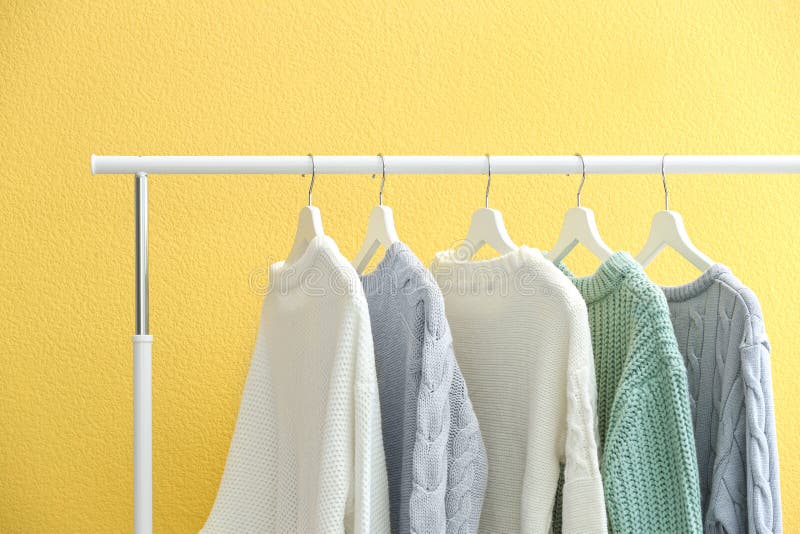 Collection of Warm Sweaters Hanging on Rack Near Wall Stock Photo ...