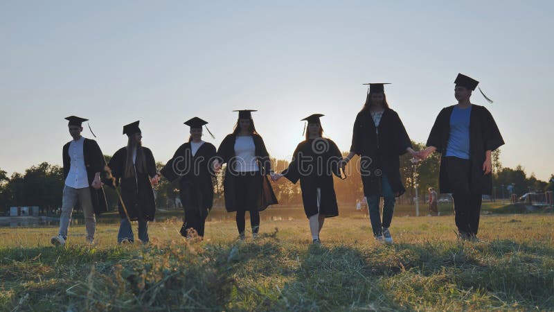 College Graduates Walk at Sunset Holding Hands. Stock Image - Image of ...