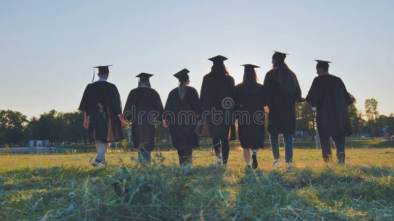College Graduates Walk at Sunset Holding Hands. Stock Image - Image of ...