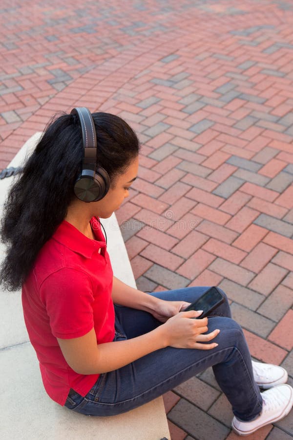 College Student with Headphones and Looking at a Cell Phone Stock Image ...
