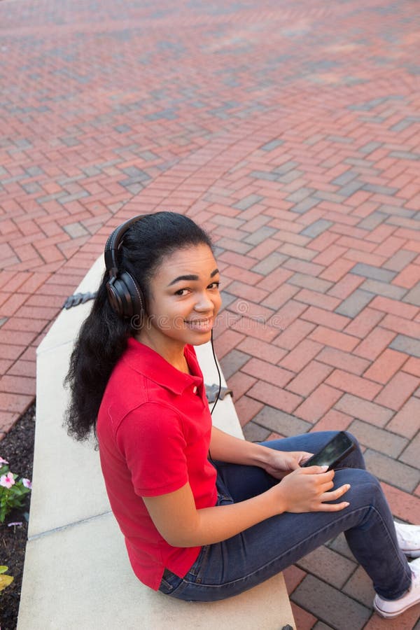 College Student with Headphones and Looking at a Cell Phone Stock Image ...