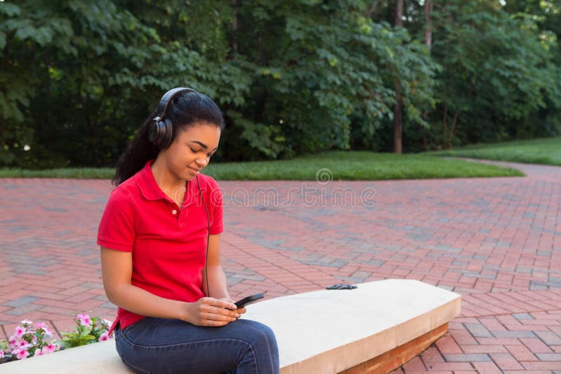 College Student with Headphones and Looking at a Cell Phone Stock Image ...