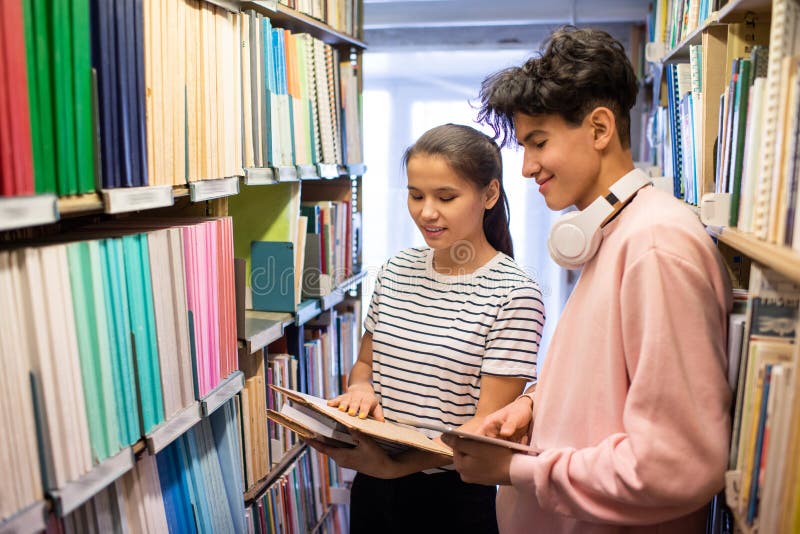 College Student with Tablet and His Classmate Looking through Book in ...