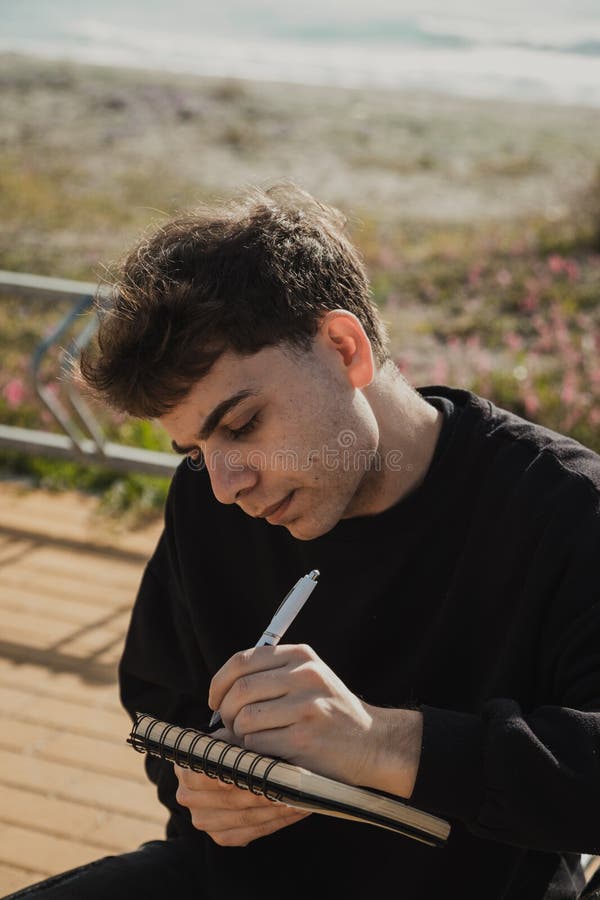 College Student Writing Notes and Studying on a Bench Near the Ocean ...
