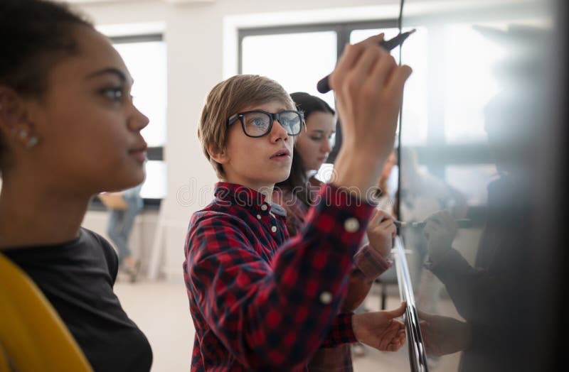 College Student Writing on White Board, Solving Problem with Classmates ...