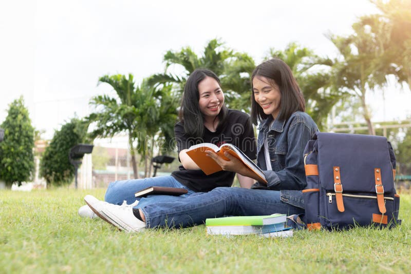 College Students Reading Book Together for Exam on Grass Field at ...