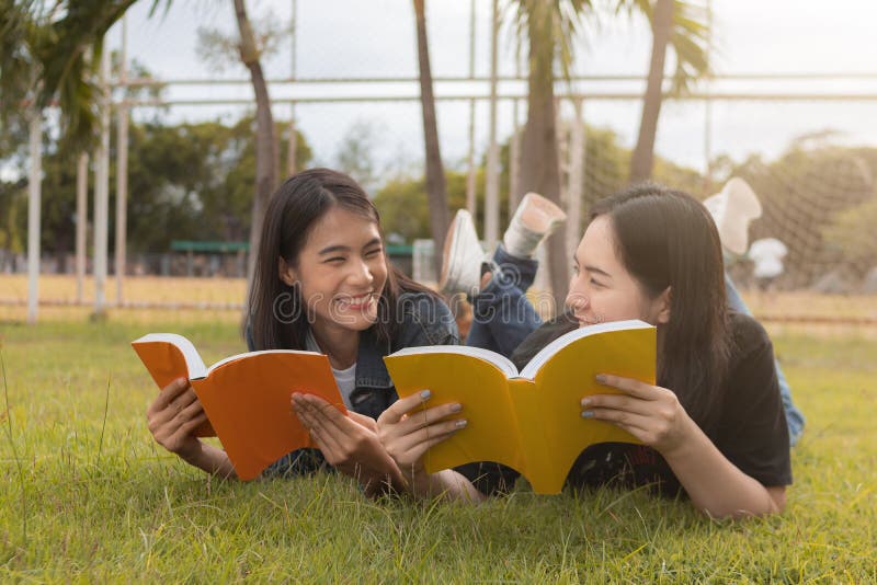 College Students Reading Book Together for Exam on Grass Field at ...