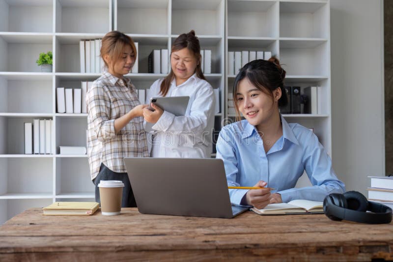 College Students Using Laptop while Sitting at Table. Group Study for School Assignment. Stock ...
