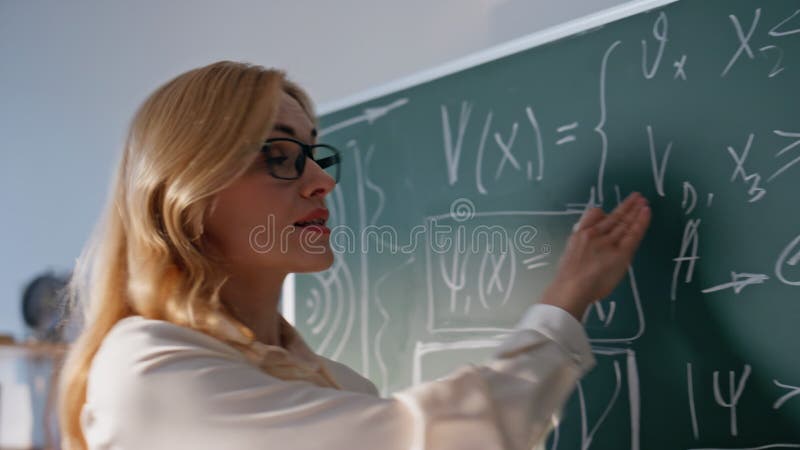 College Teacher Teaching Class Showing Physics Formulas on Blackboard ...