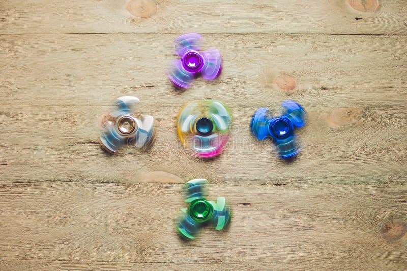 Colored Fidget Spinners Stress Relieving Toy on Wooden Background Stock ...