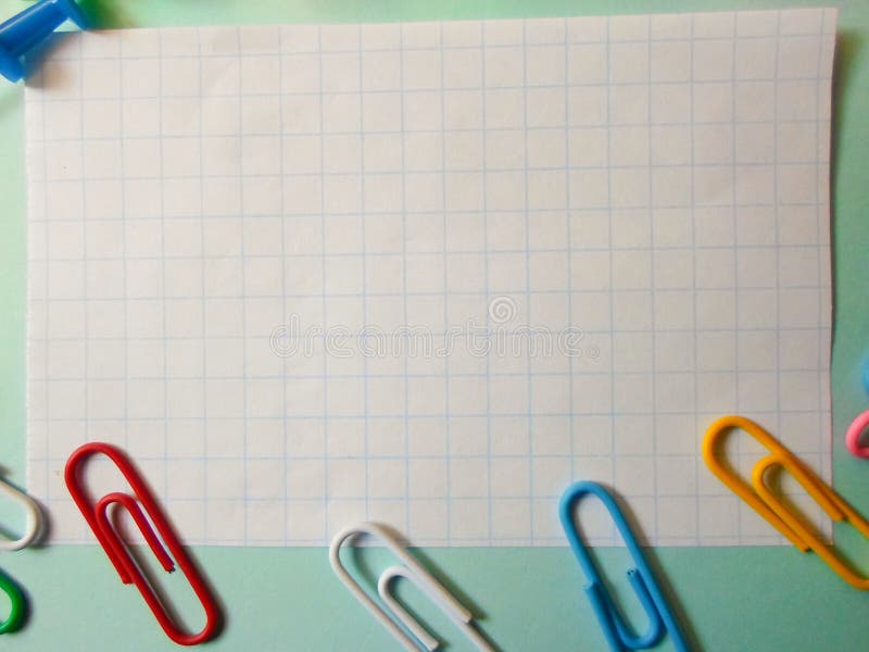 Colored Paper Clips and Pins on a White Sheet of Paper are Scattered ...