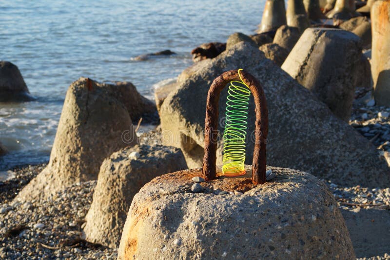 Colored Plastic Spring on a Rusty Loop of Reinforced Concrete Shore ...