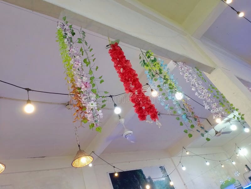 Colorful Artificial Flower Garlands and String Lights Hang from a White ...