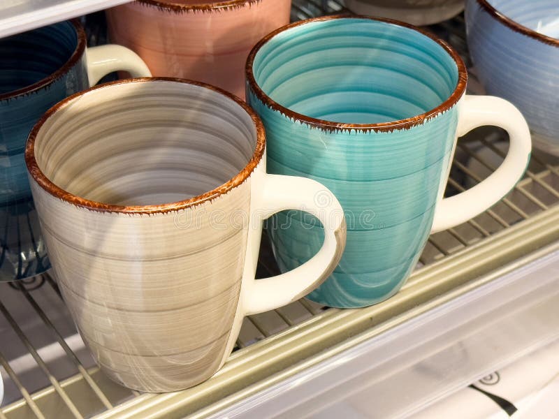 Colorful Ceramic Mugs Displayed on Metal Shelf in Store Setting ...