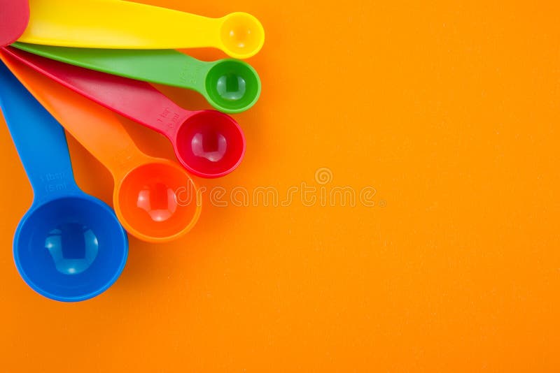 Colorful Measuring Spoons on Orange Paper Background Copy Space. Stock ...