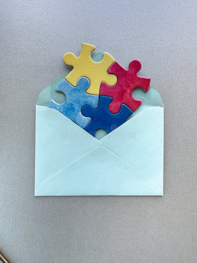 Colorful Puzzle Pieces Emerging from a Light Blue Envelope on a Gray ...