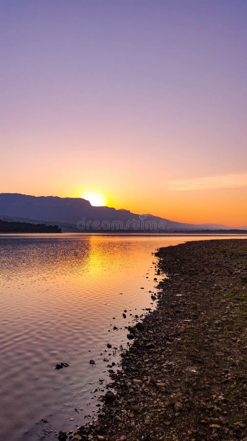 Colorful Sunset Over Water and Behind Mountain Range Stock Image ...