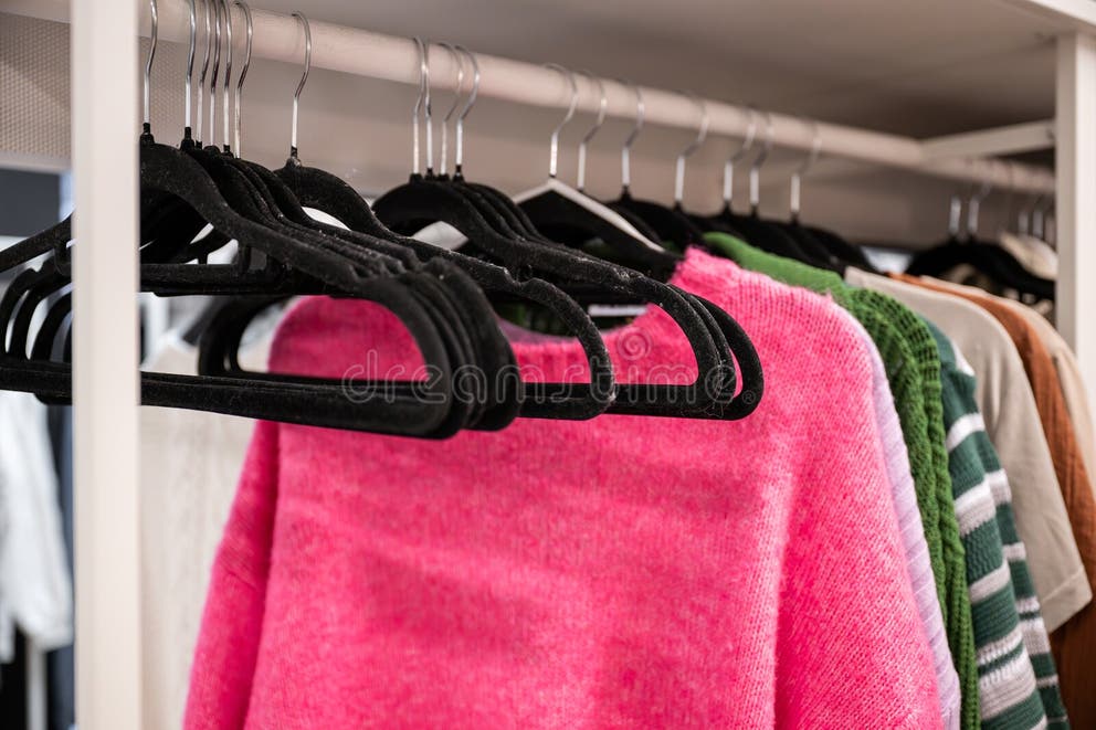 Colorful Sweaters and Empty Black Hangers in a Thrift Store Stock Image ...