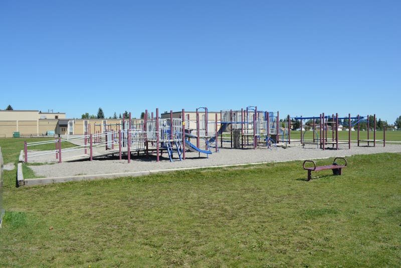 Colourful Playground in Grassy School Yard with School in Background ...