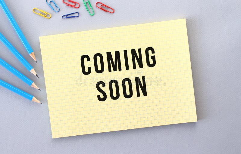 COMING SOON Text in Notebook on Gray Background Next To Pencils and ...