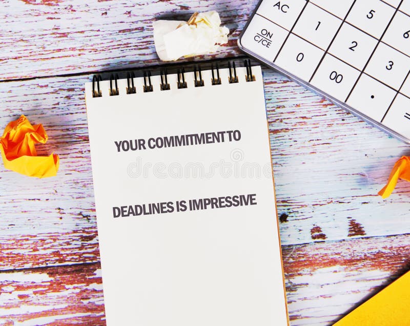 Commitment To Meeting Deadlines Noted on Notepad Alongside a Calculator and Crumpled Paper in a ...