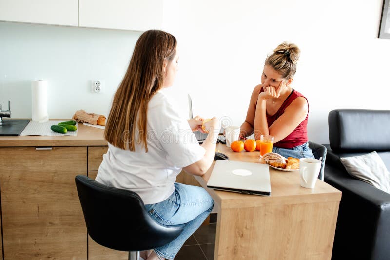 Communication . Two Cute Girlfriends are Sitting in Kitchen Talking ...