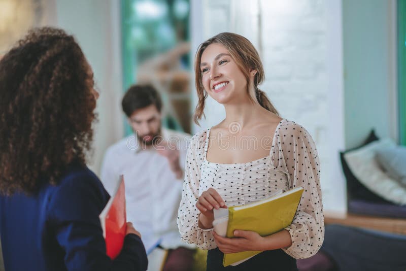 Two Talking Girls with Documents and Guy Behind Stock Image - Image of ...