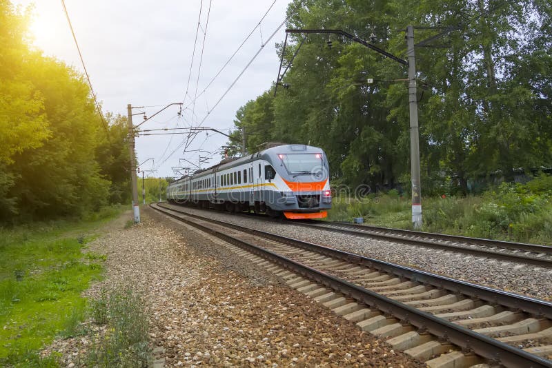 Commuter Train Rides on Railway Tracks in City with Green Trees in ...