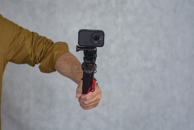 Compact Action Camera on a Flexible Tripod in Hand on a Light ...