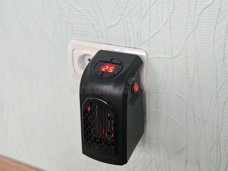 Compact Electric Heater Plugged into a Wall Outlet Displaying a ...