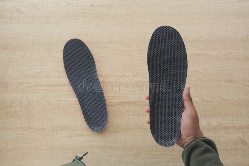 Comparison of Shoe Insoles Held in Hand Above Wooden Surface Stock ...