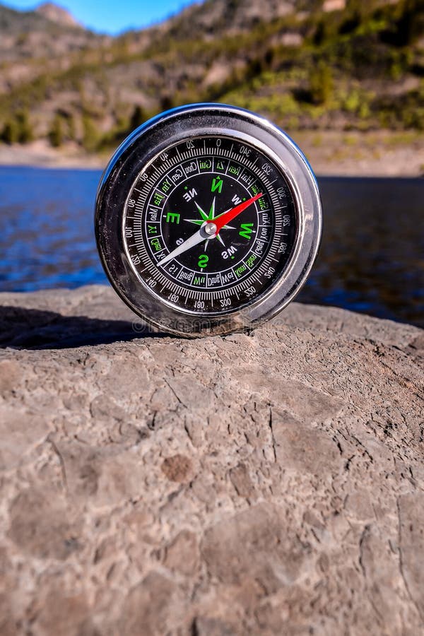 A Compass is Sitting on a Rock by a Body of Water Stock Image - Image ...