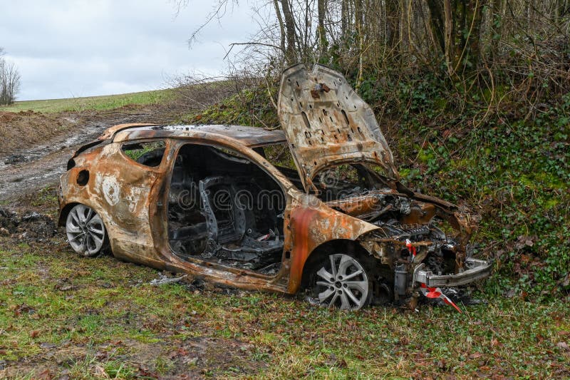 A Completely Burned and Rusted Car Wreck is Abandoned on the Side of a ...