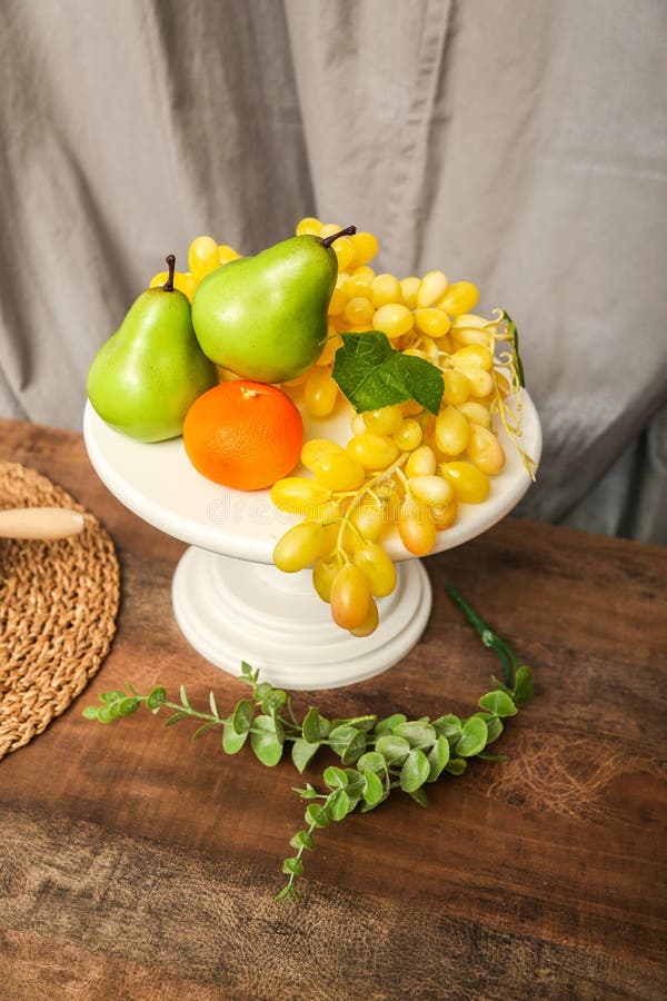 A Composition of Different Fruits on a White Stand Stand on a Wooden ...
