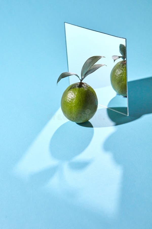 Lime with Green Leaves and a Mirror on a Blue Background with Shadows ...