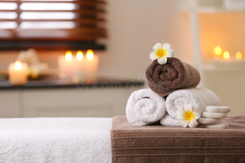 Composition With Towels Flowers And Stones On Massage Table In Spa
