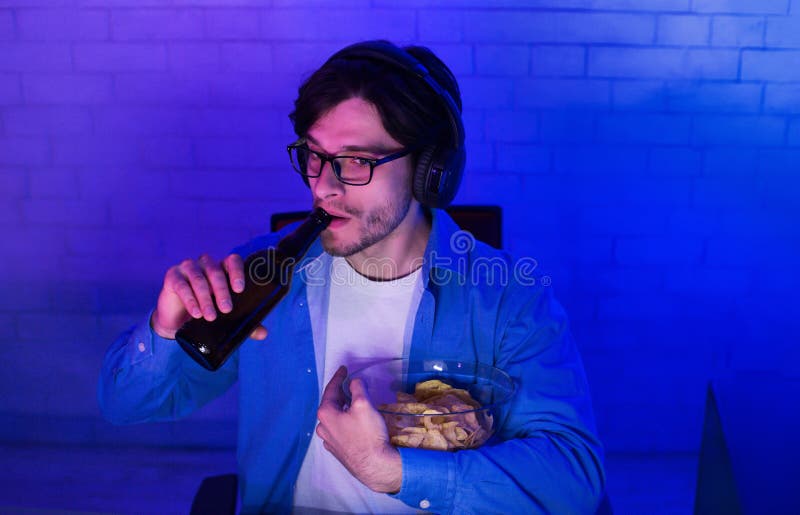 Millennial Guy Playing Online Game Drinking Beer at Home, Low-Light ...