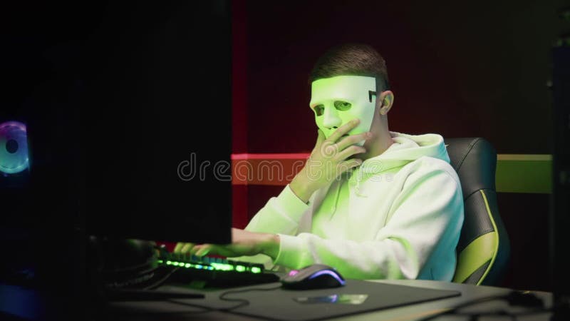 A Masked Hacker Breaks into a Database on a Computer, Hacking in a Dark ...
