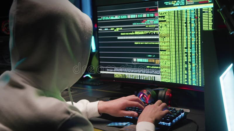 A Masked Hacker Breaks into a Database on a Computer, Hacking in a Dark Room Stock Footage ...